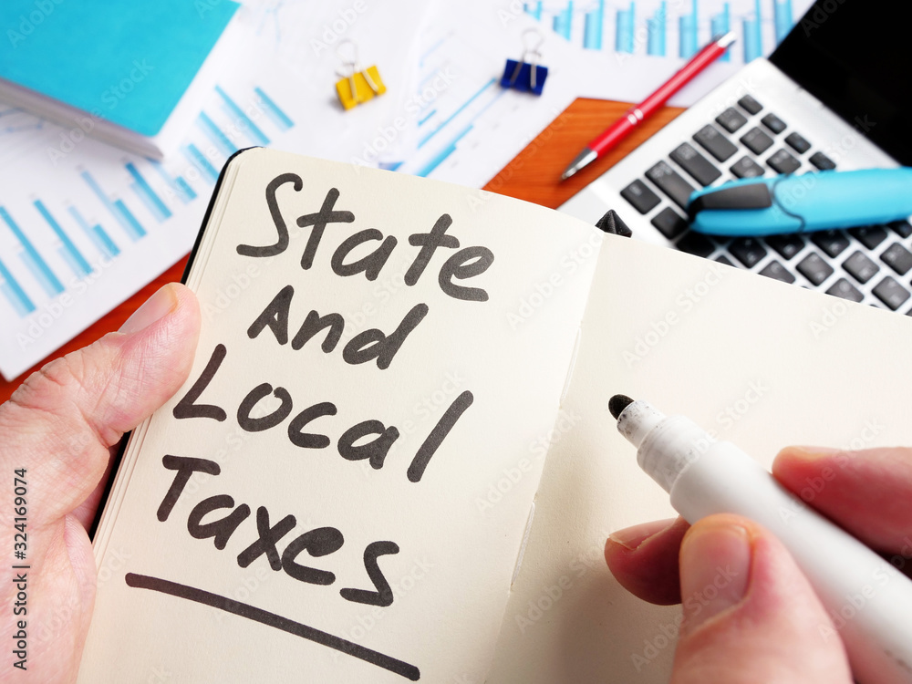 Man calculating State and Local Taxes in the note. Stock Photo | Adobe ...