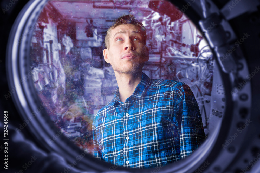 young male space tourist looking through the window of a spaceship and ...