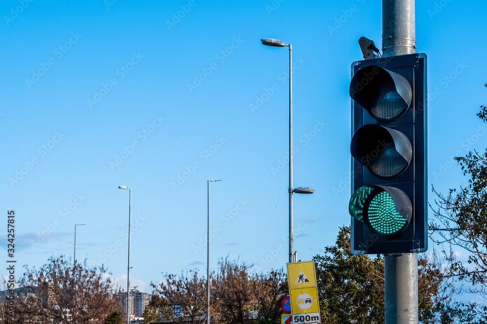 Green traffic lights and traffic signs on city street Stock Photo ...