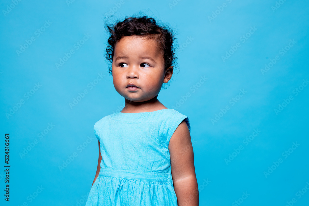 Portrait of little girl wearing light blue dress against blue ...