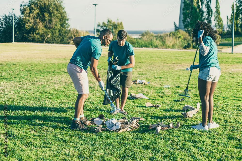 Cleaning workers in uniforms removing garbage from grass. Men and woman ...