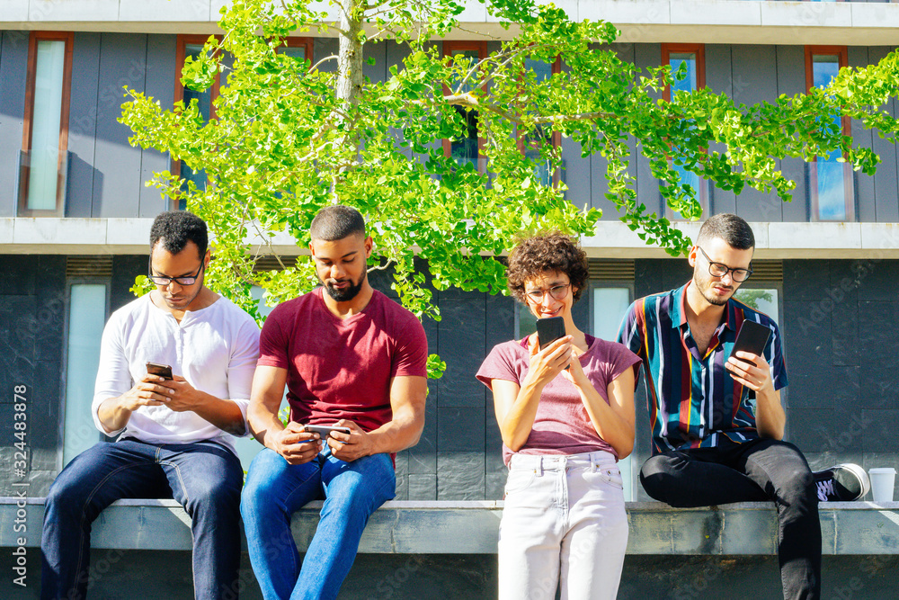 Four friends totally excited with their mobile phones. Men and woman ...