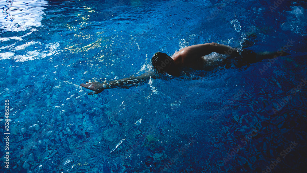 Professional male swimmer crawls underwater in a blue swimming pool ...
