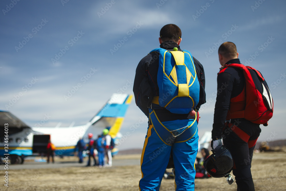 Figures of two skydivers with parachutes preparing for take-off against ...