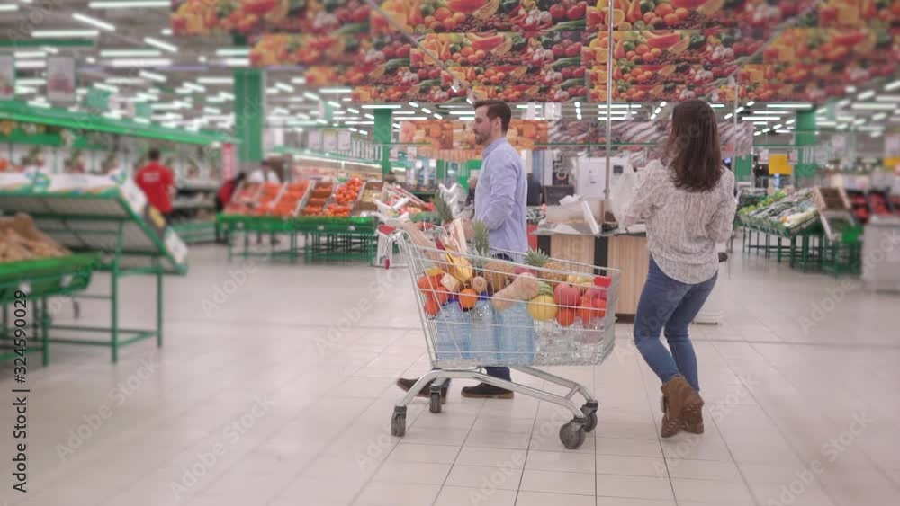 Attractive couple dancing and laughing in supermarket through fresh ...