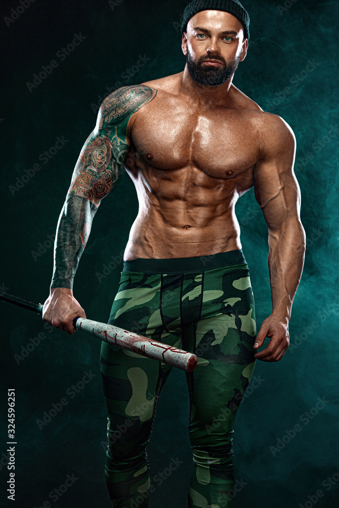 Strong and fit man bodybuilder with baseball bat shows abdominal ...