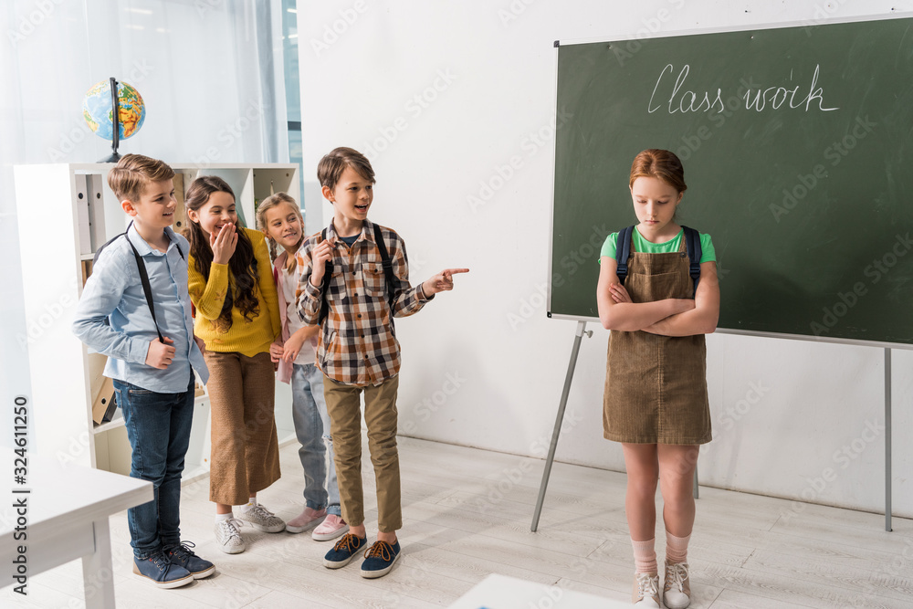 cruel schoolkid pointing with finger and laughing near bullied ...