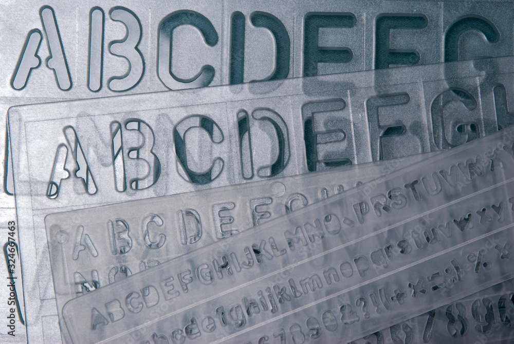 Clear plastic alphabet stencil sheets stacked on top of each other with ...