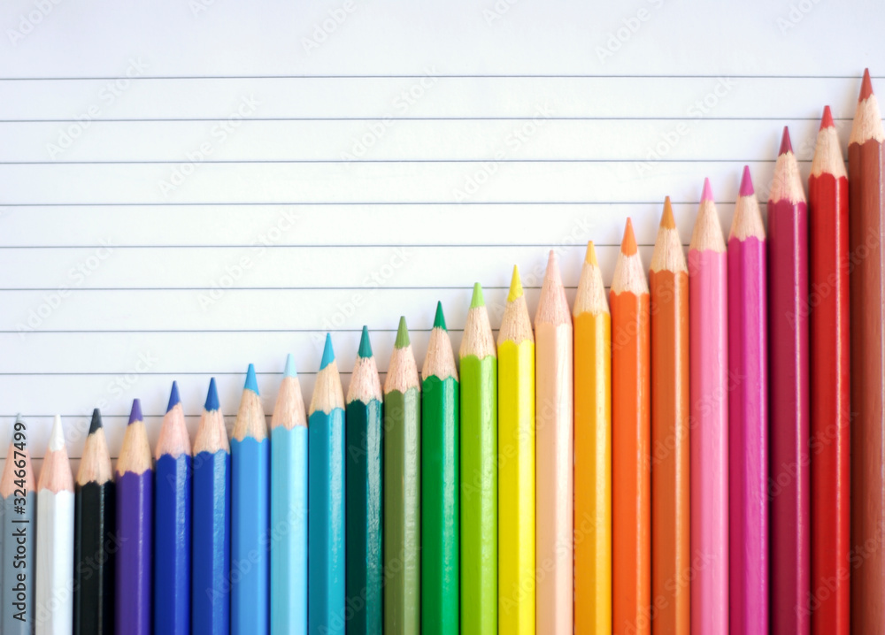 Bar chart graph rainbow of colored pencils slide up against a sheet of ...