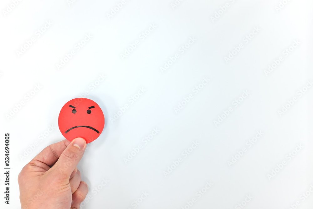 Hand holding an angry emoticon in white background with copy space ...