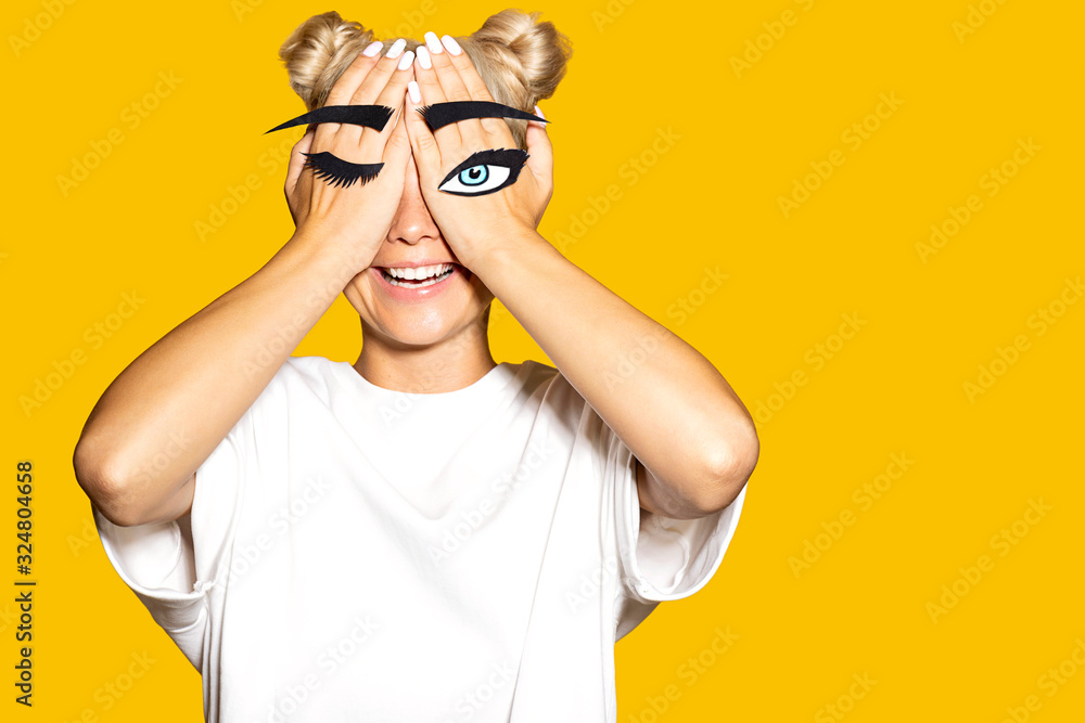Young funny woman covering face with fake giant eyebrows and eyelashes ...