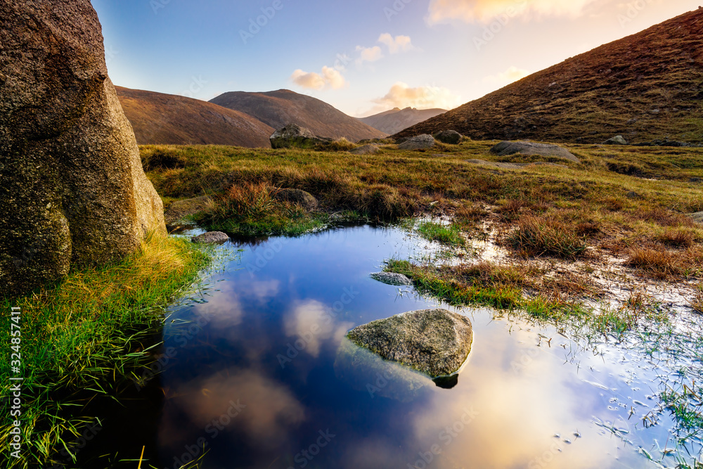 Puddle of water with reflection of blue sky and clouds on the Hares Gap ...