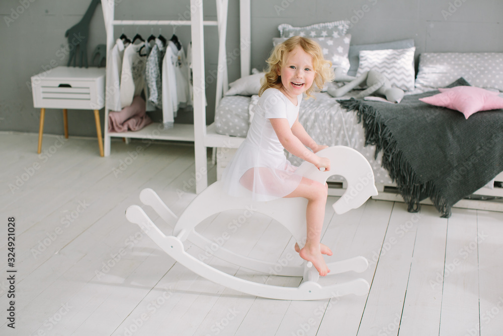 Girl child rides white horse indoor. Child girl happy face enjoy riding ...