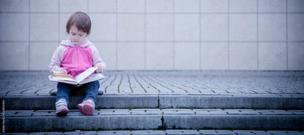 Learn аlways and everywhere. Cute little child girl watching a book ...