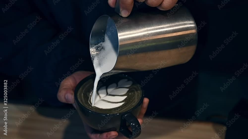 Cropped shot of Barista hand trying to pouring steamed milk to making ...