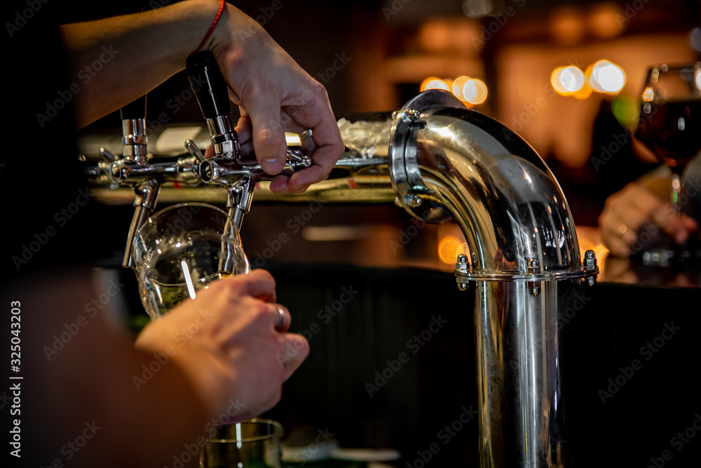 bartender hand at beer tap pouring a draught beer in glass serving in a restaurant or pub Stock ...