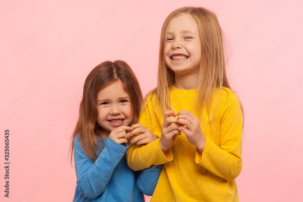 Two funny naughty little girls cunningly looking at camera and plotting ...