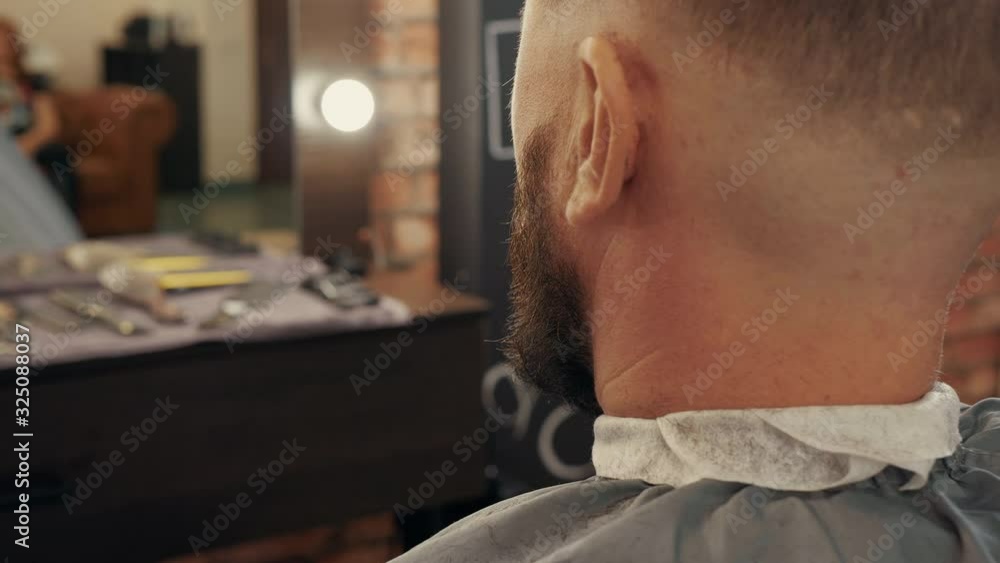 Back view of barber trimming beard of client. Rear view of hairdresser ...