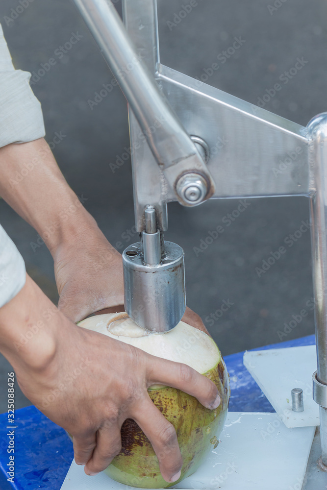 The boy use eazy cuting coconut tool at JJ market in Bangkok.๋Just ...