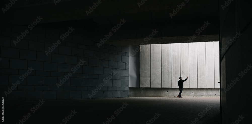 Man in a tunnel exit looking up and raising his hand up Stock Photo ...