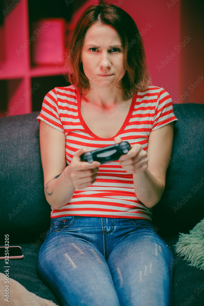 Girl playing a video game at living room at night. Gamer woman sitting ...