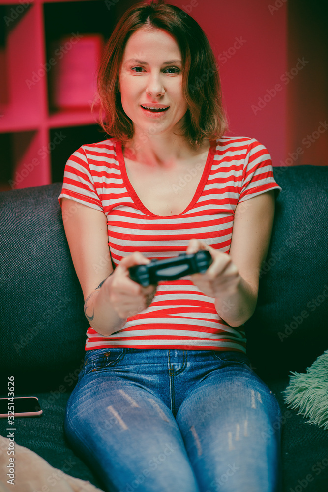 Determined girl playing a video game at living room at night. Gamer ...