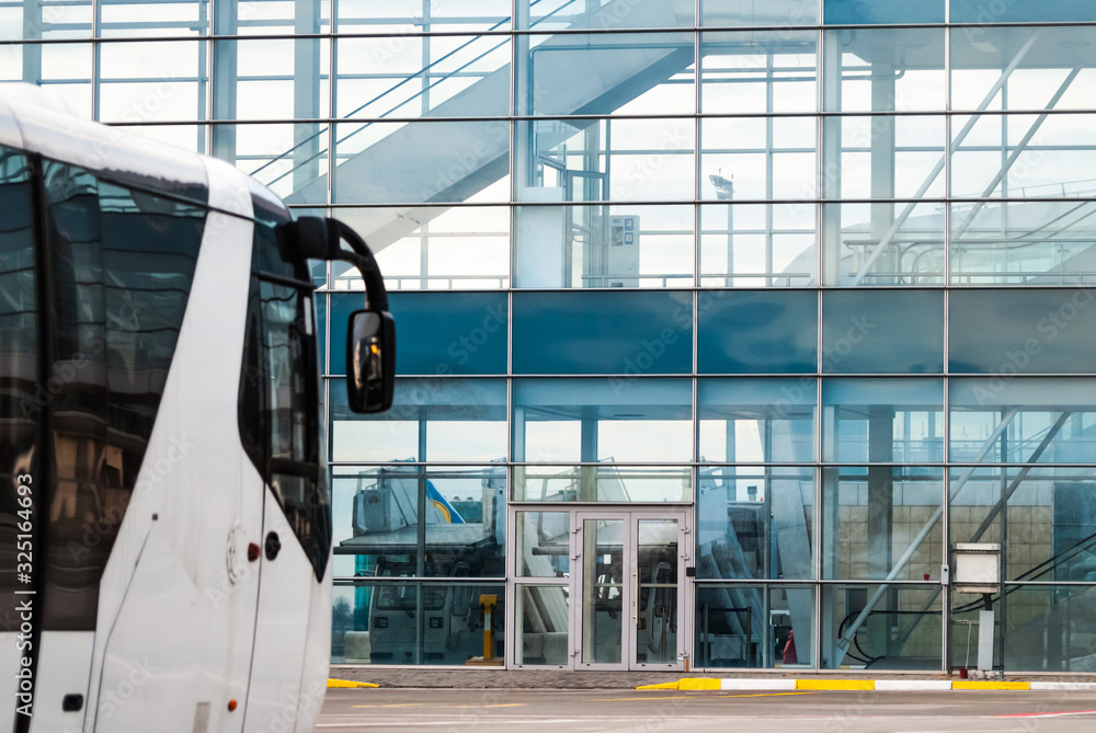 White modern tour bus and glass building. Shuttle bus in the airport ...