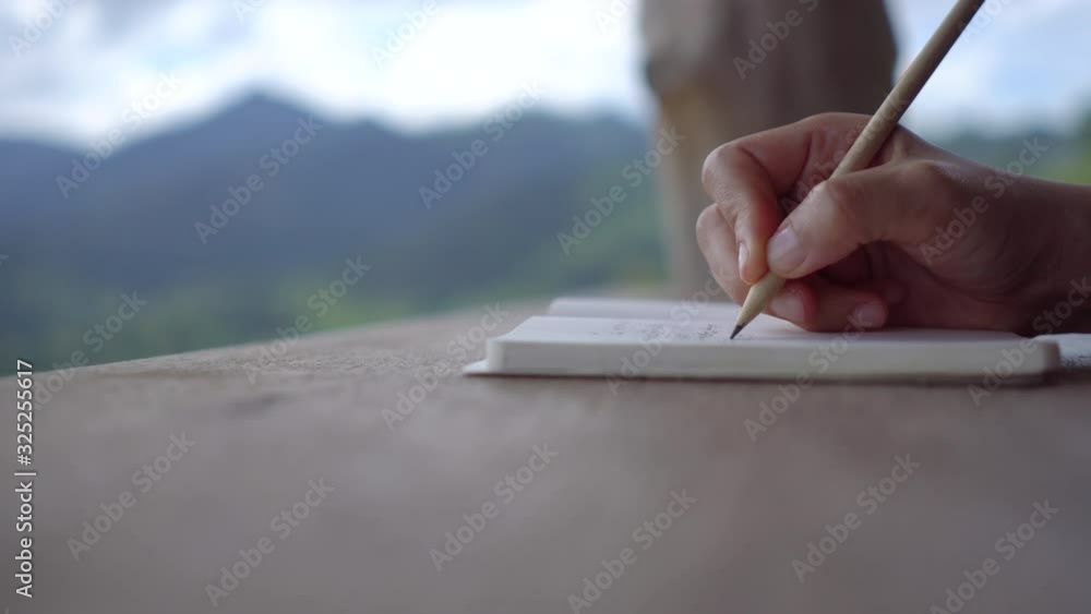 4K video of woman hand writing down in white notebook with work space ...