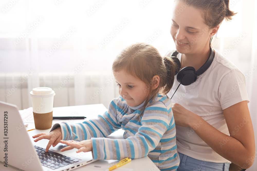 Close up portrait of woman and young cute girl sitting in front of ...