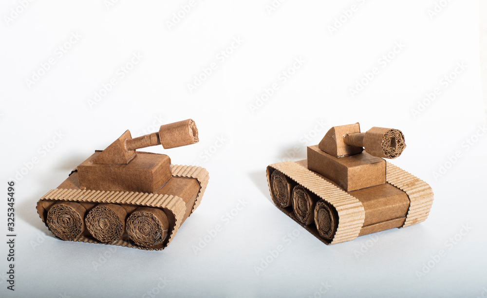 two toy tanks made by children from corrugated cardboard are fighting ...