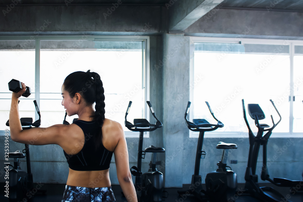 Healthy lifestyle of young people. Happy Asian woman workout in gym to ...