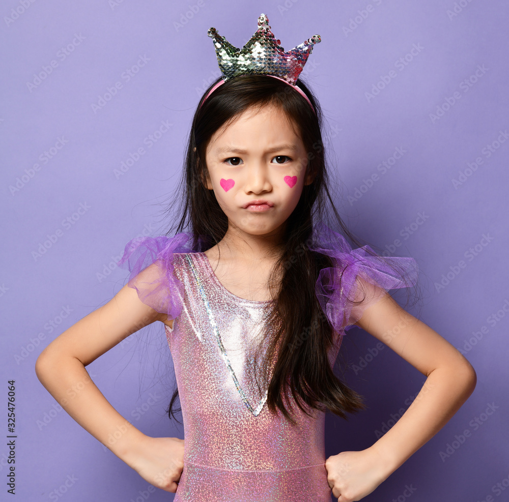 Unhappy mad asian kid girl in party dress, crown and with a painted red ...
