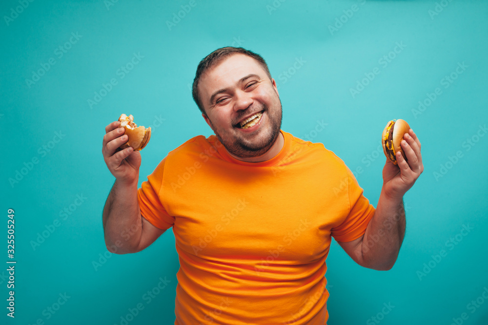Emotional happy fat man on a blue background eating fast food ...