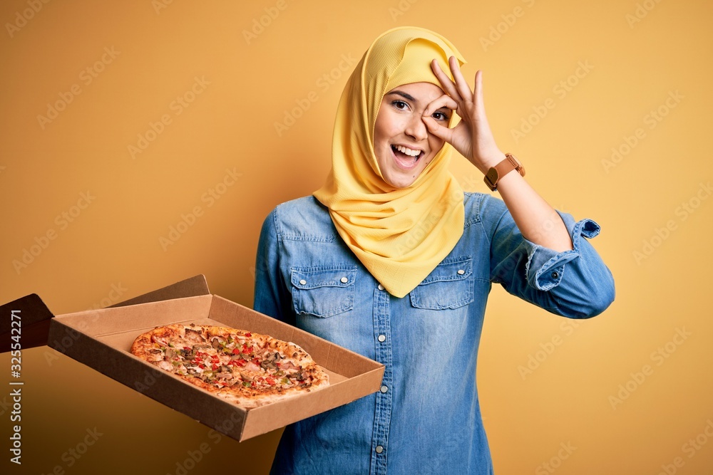 Young girl wearing muslim hijab holding box with Italian pizza over ...