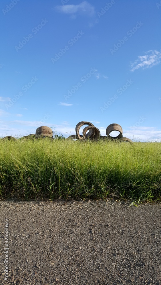 Manilhas de cimento em meio a relva verde com céu azul ao fundo foto de ...