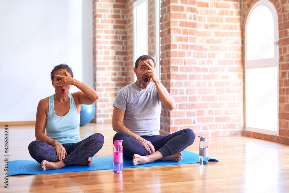 Middle age sporty couple sitting on mat doing stretching yoga exercise ...