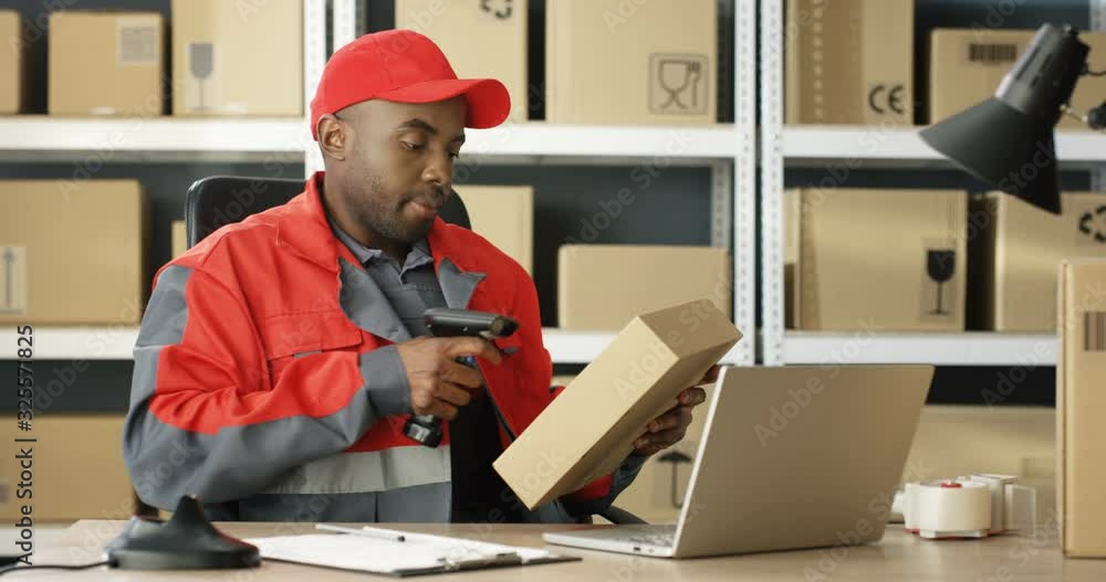 African American mailman in uniform working at laptop computer in post ...