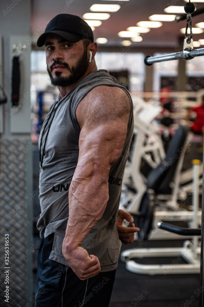 strong powerful athlete man with beard wearing cap and wireless headset ...