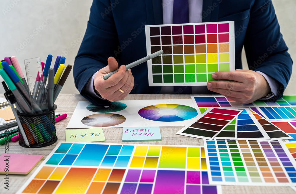 graphic or interior young designer in suit choosing color from swatch ...