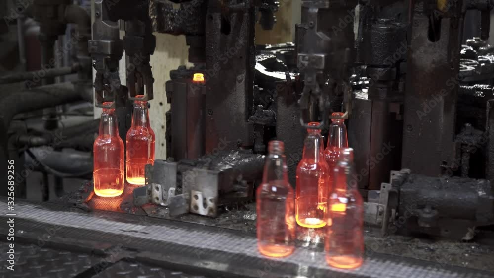 The heated glass bottles melted from quartz sand move along a conveyor ...
