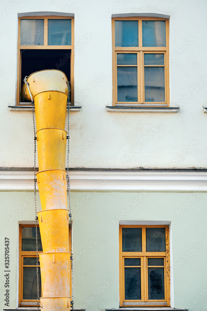 Yellow telescope rubble chute. Plastic garbage chute fixed on facade ...