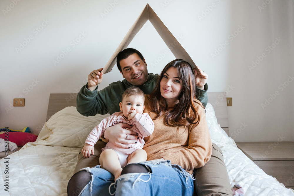 Portrait of a family on the bed at home with their baby girl - Father, mother and one year old ...