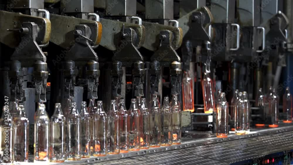 The heated glass bottles melted from quartz sand move along a conveyor ...
