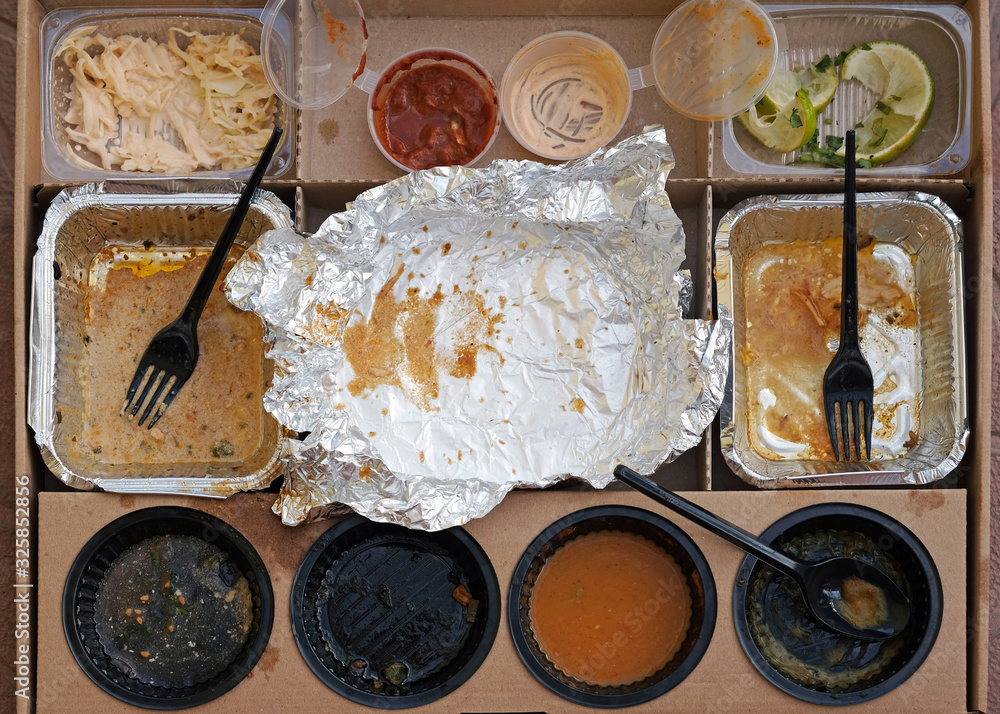 Box of fast food, empty plates with forks, sauces and aluminum bowls ...