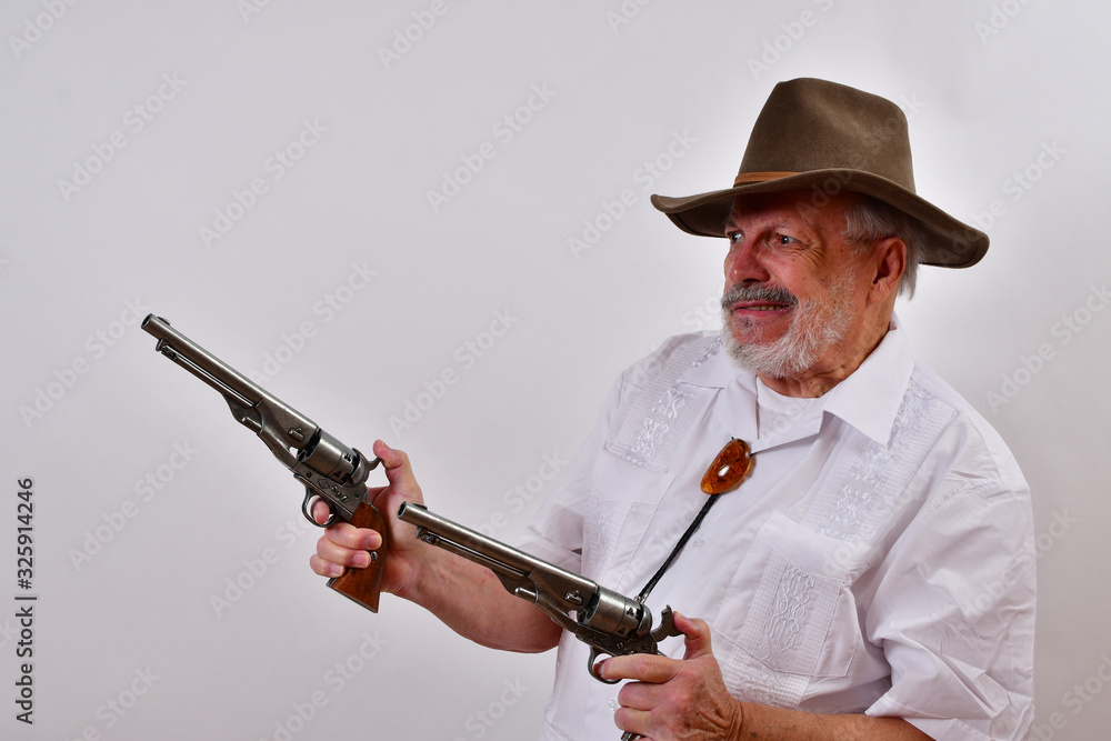 Angry old man aims two revolvers..Elderly gentleman with floppy hat and ...