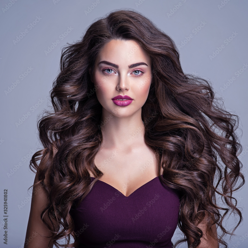 Face of a beautiful woman with long brown curly hair. Fashion model ...