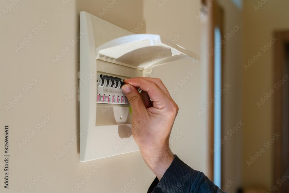 Hand switching power switch on a fusebox. Close up of electrician ...
