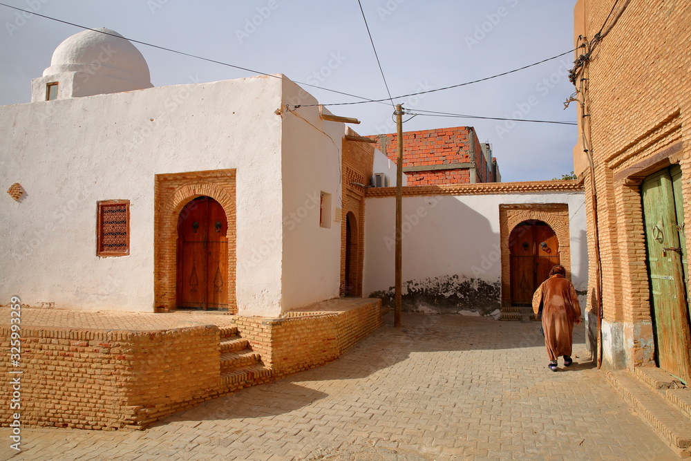 Typical cobbled and narrow street inside the brick decorated medina of ...