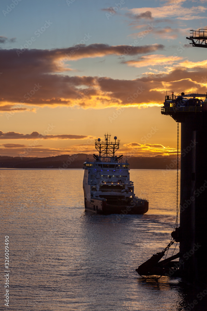 Offshore vessel doing Rig Move with Semi Submersible oil rig at sunrise ...