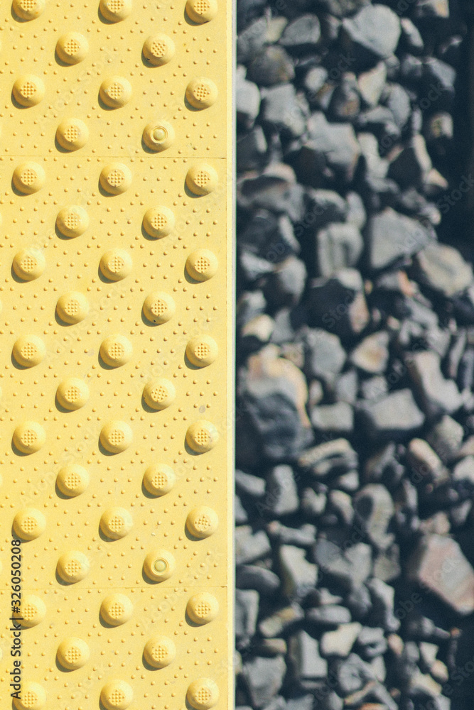 Train station platform yellow curb with Track ballast gravels and ...